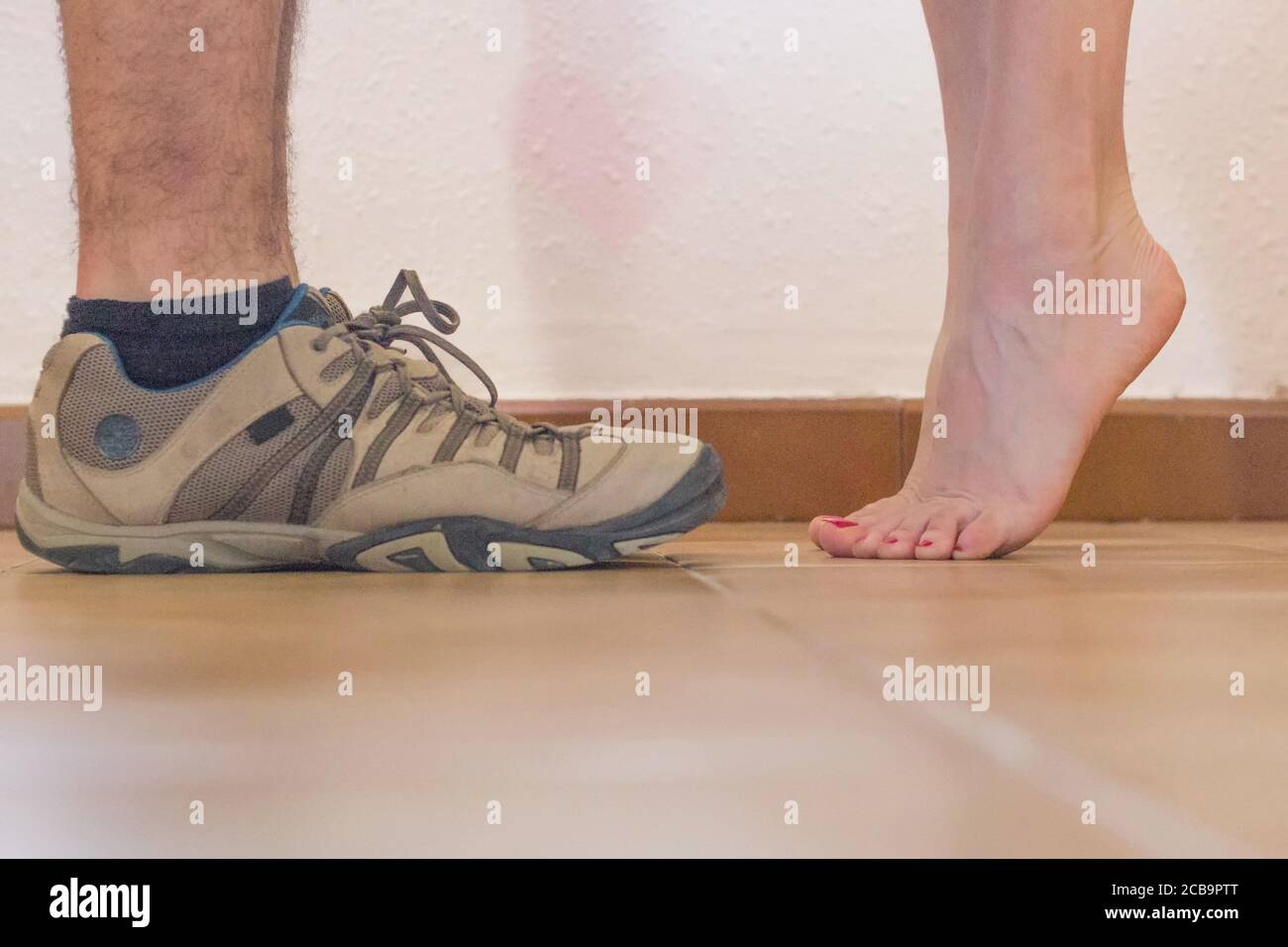 Barefoot girl on tiptoes to hug her man at home, the couple kissing ...