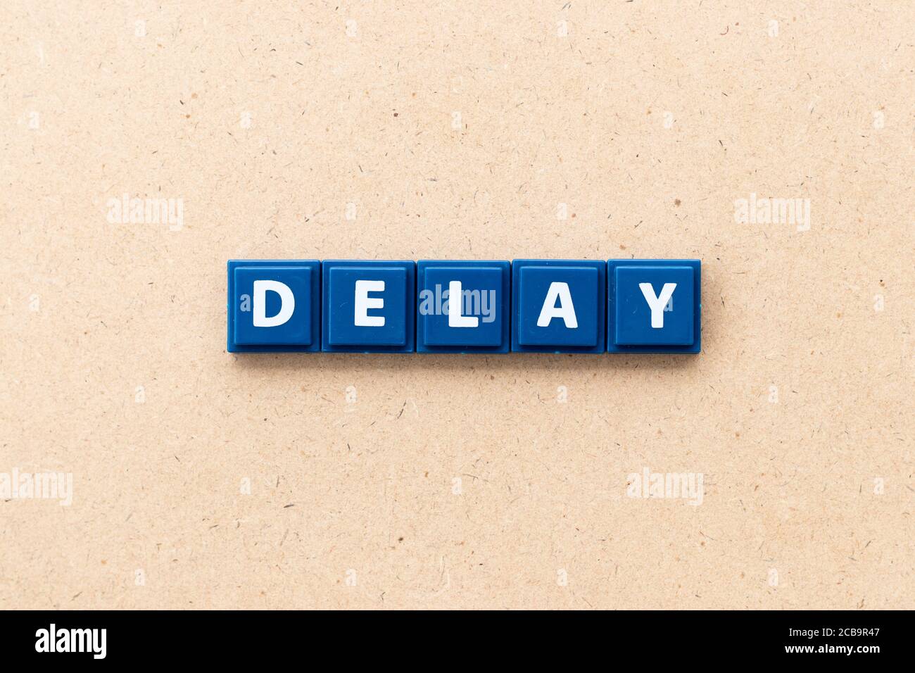 Tile letter in word delay on wood background Stock Photo - Alamy