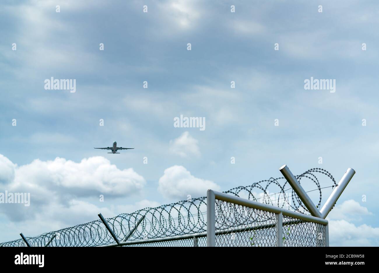 Airplane flying on blue sky and white clouds above metal fence ...