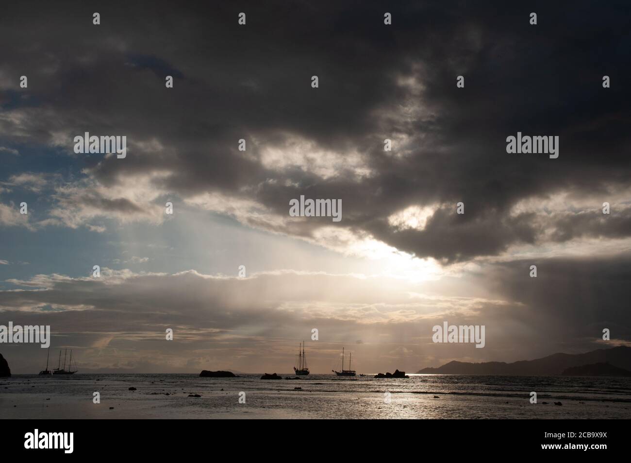 Dramatic sky with clouds and sunbeam over the Indian Ocean with sailing ...