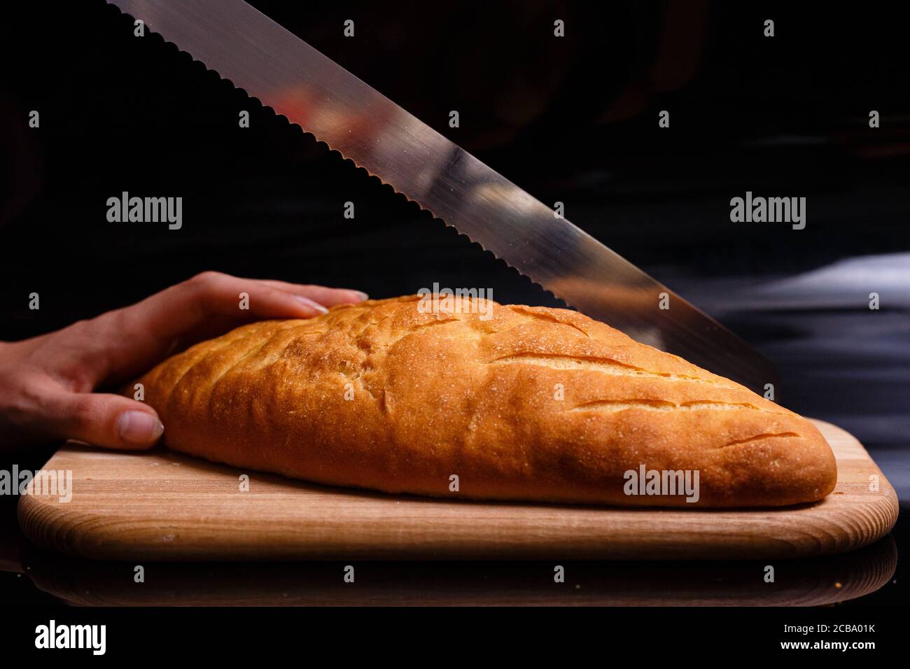 Homemade white bread is cut with a large knife. Baking at home Stock ...
