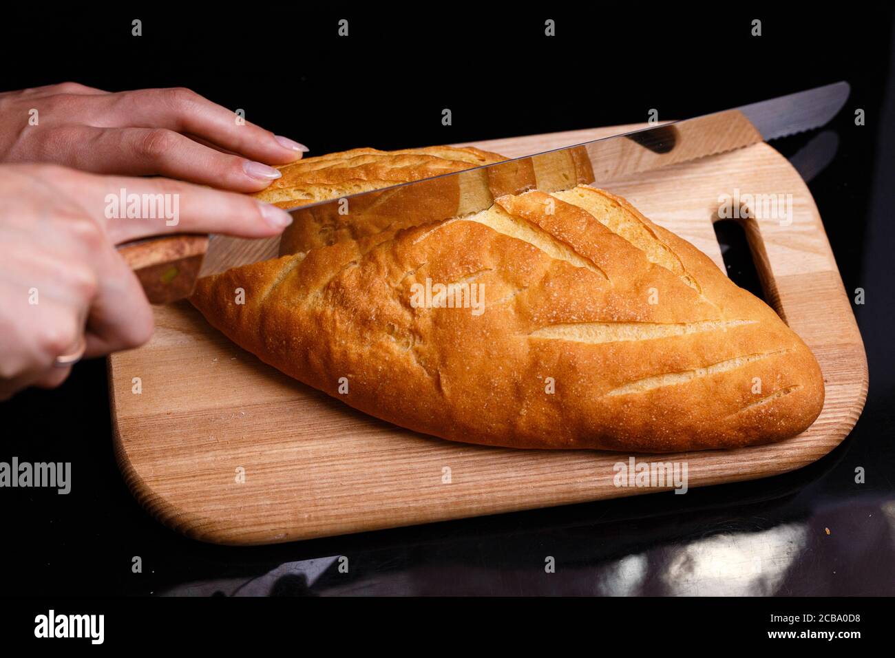 Homemade white bread is cut with a large knife. Baking at home Stock ...