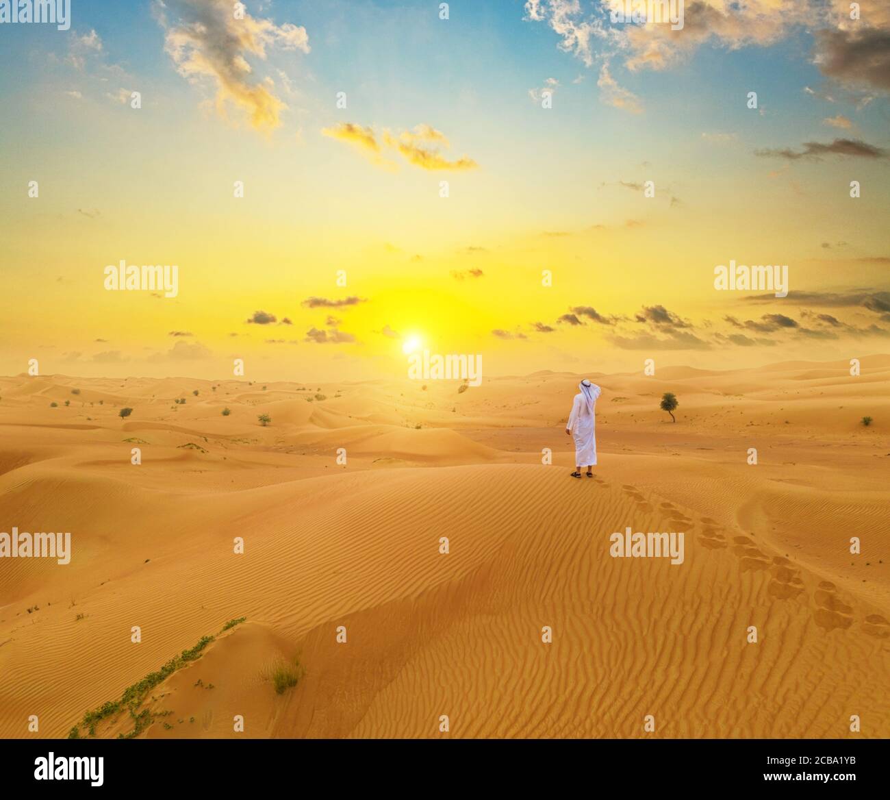 Arabian man walking at desert during sunset. dressed in traditional ...