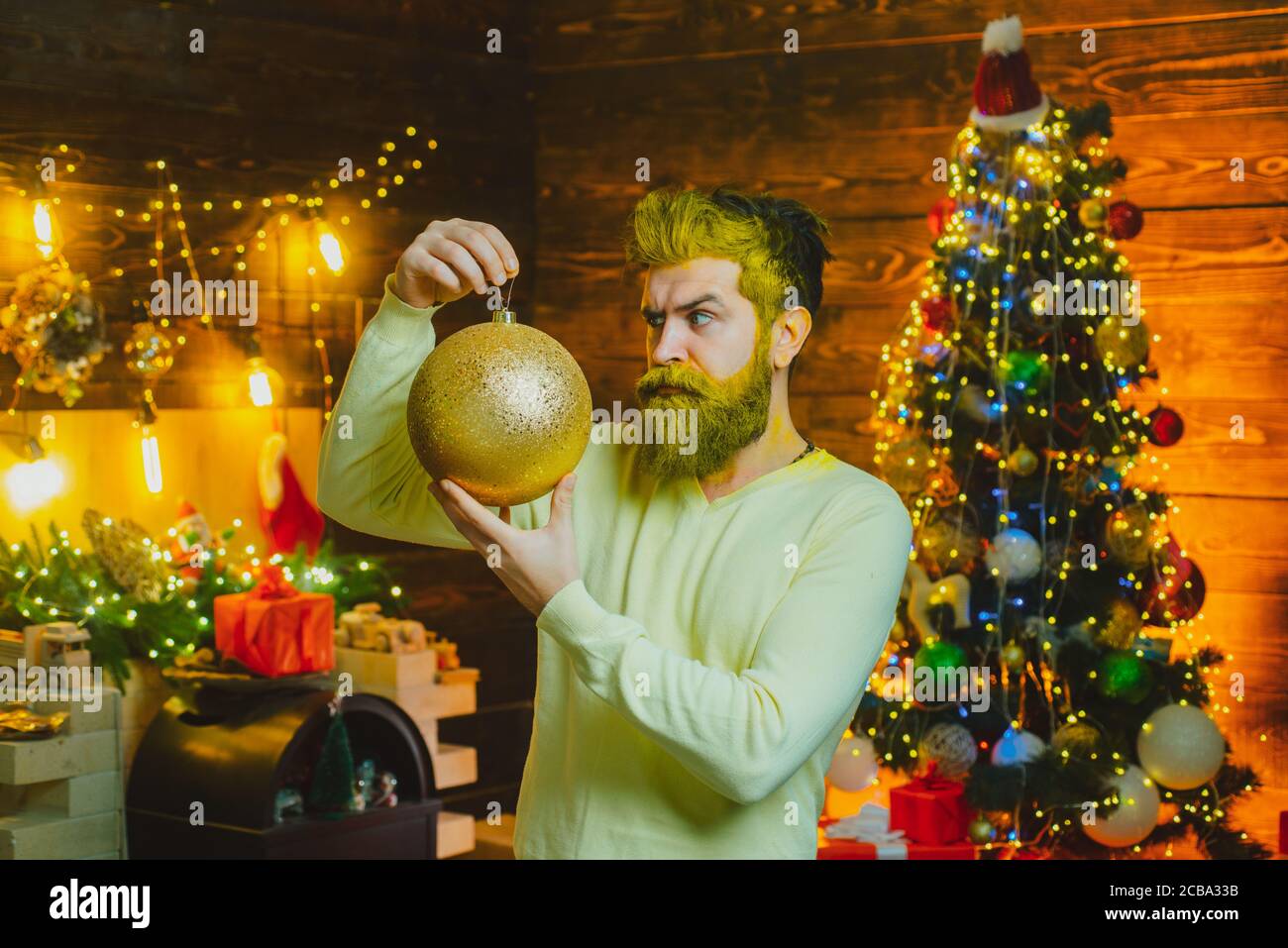 Portrait of handsome Santa man indoors with Christmas ball, gold bauble ...