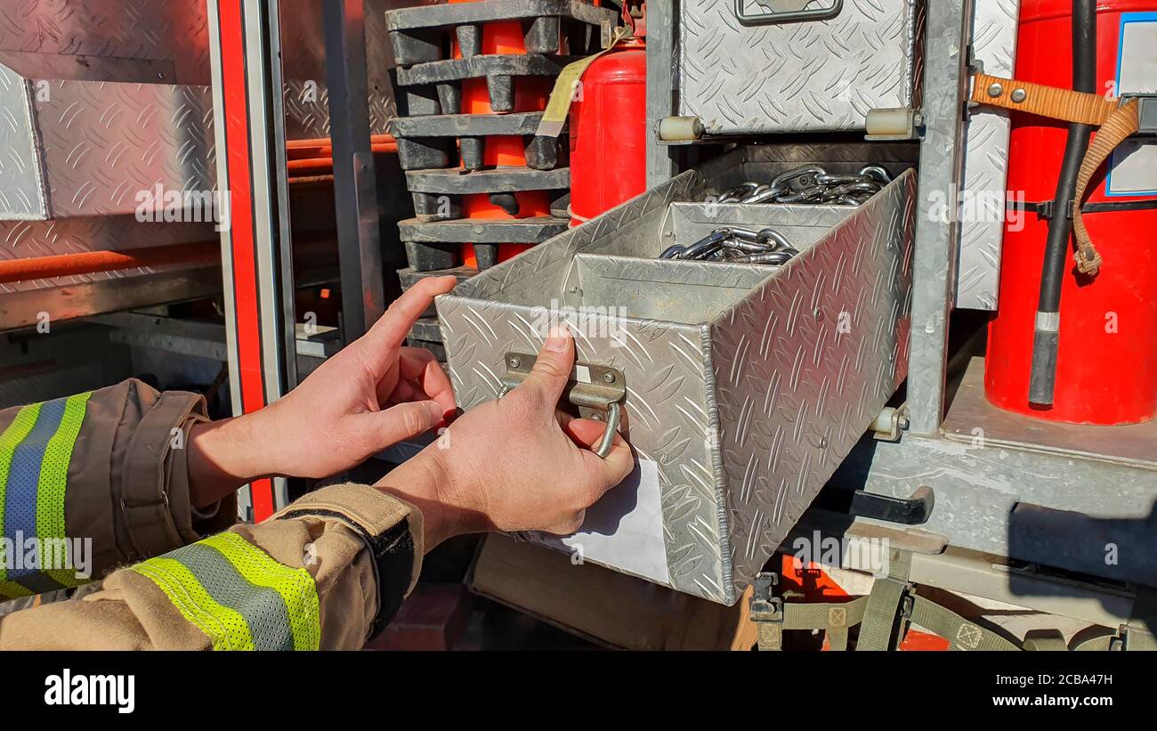 Closeup of a caucasian man firefighter opening a drawer full of chains ...