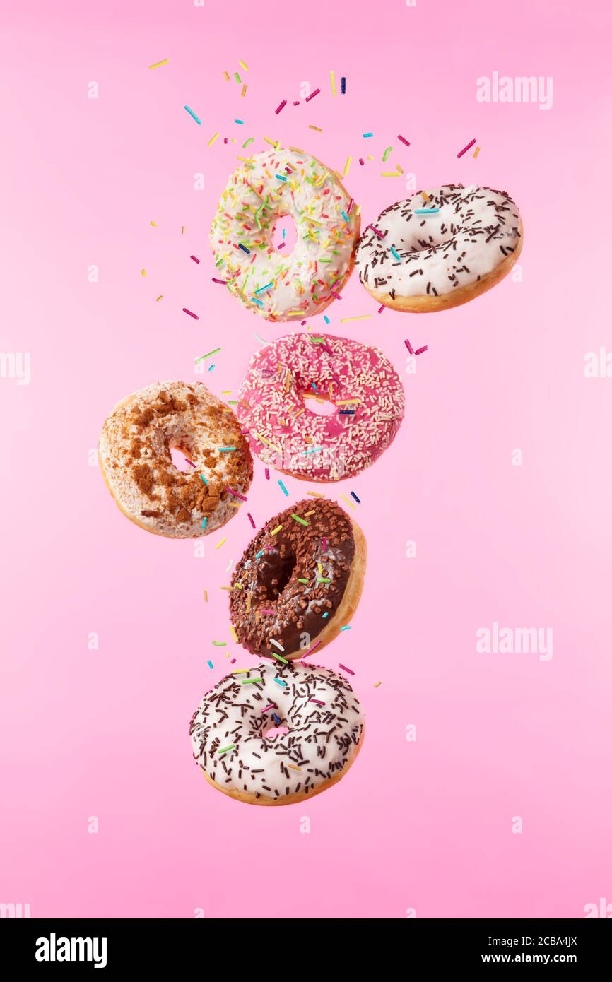 Flying sweet donuts isolated on pink background. Concept of low gravity ...