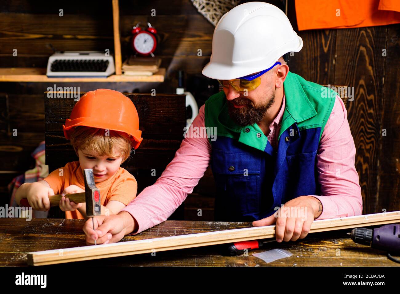 Dad shows his boy how to make diy in wooden workshop using hammer and ...