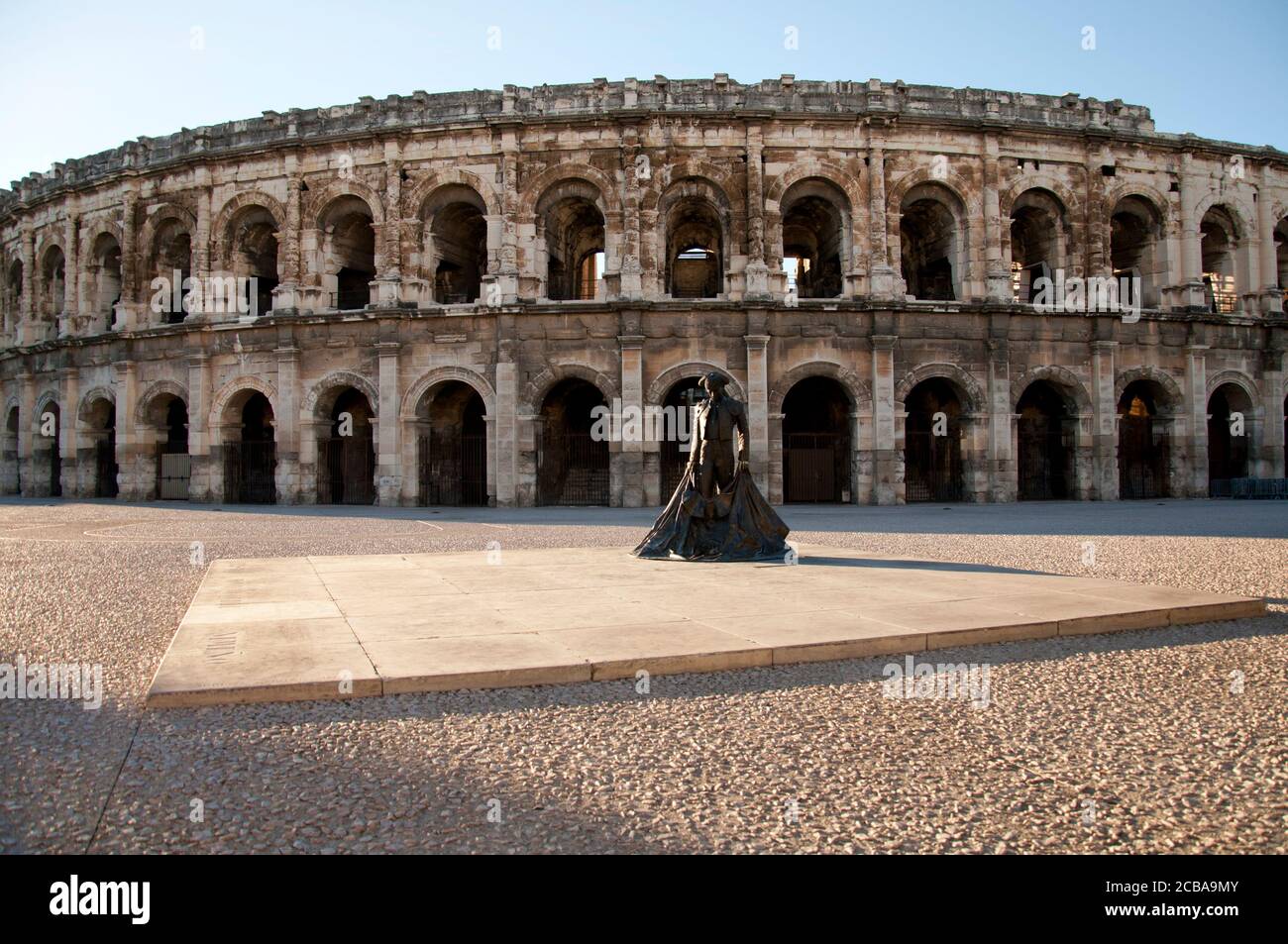 Bullfighter statue and the elliptical Roman amphitheatre in Nimes in ...