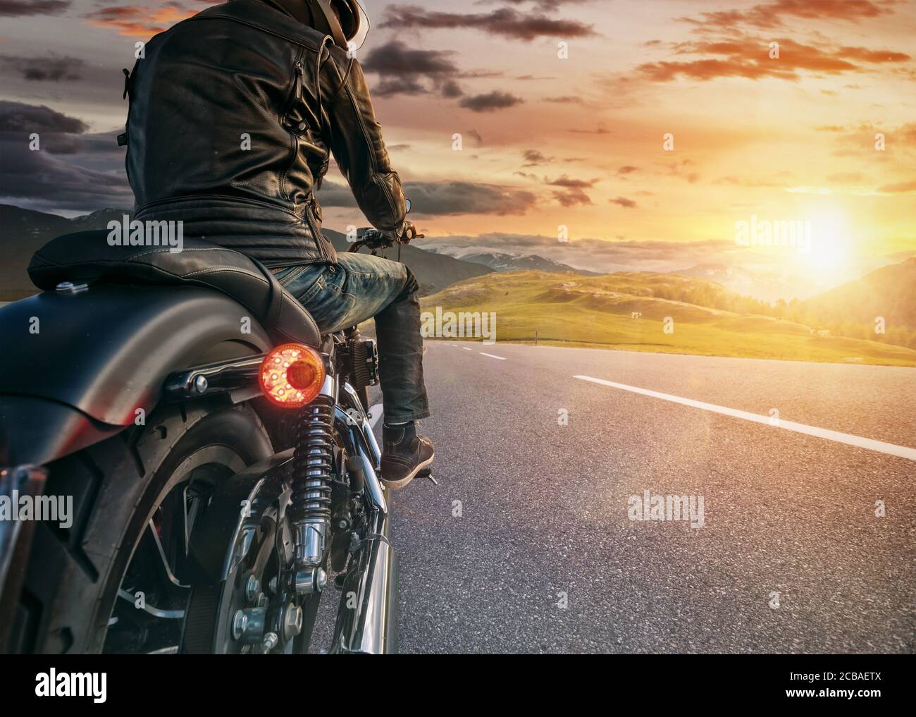 Motorcycle rider ready for drive in Alps, beautiful sunset dramatic sky ...