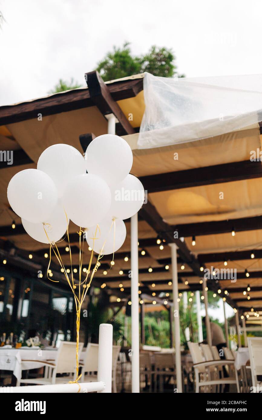 A bunch of white helium balloons on the background of tables in the ...