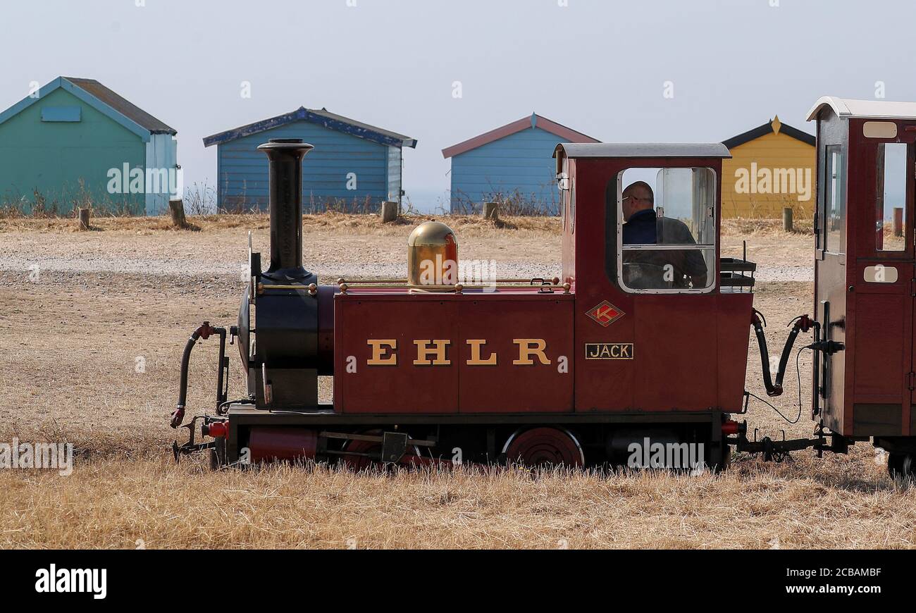 A locomotive from the Hayling Seaside railway passes beach huts as it ...