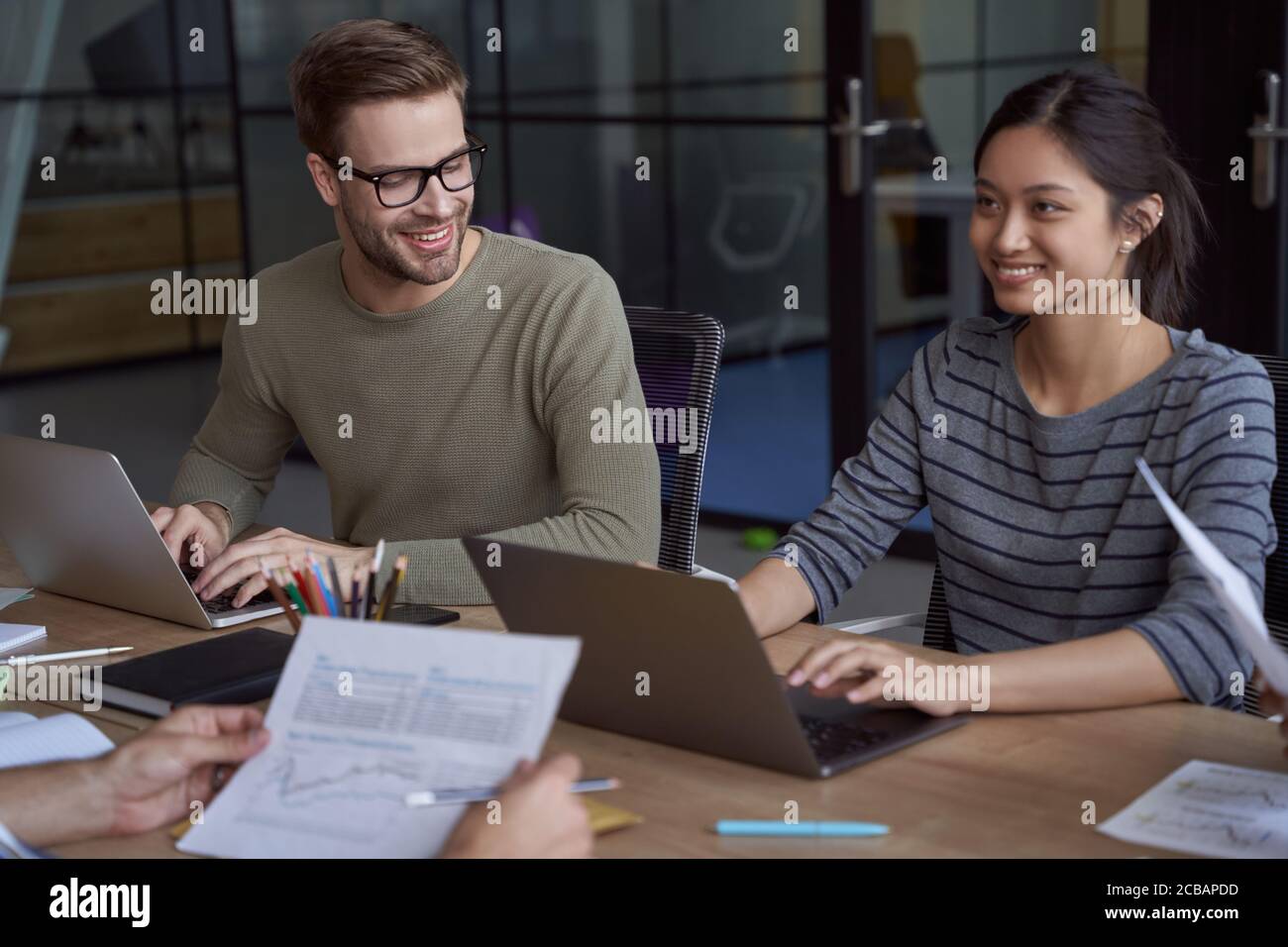 Working together. Young happy female and male colleagues, happy coworkers working on laptops and ...