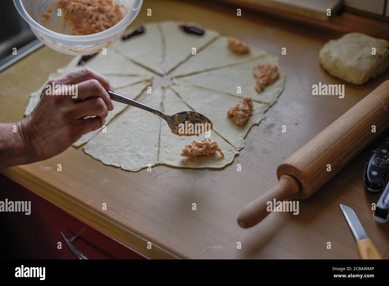 Closeup shot of a person making pastries and adding filling to dough ...