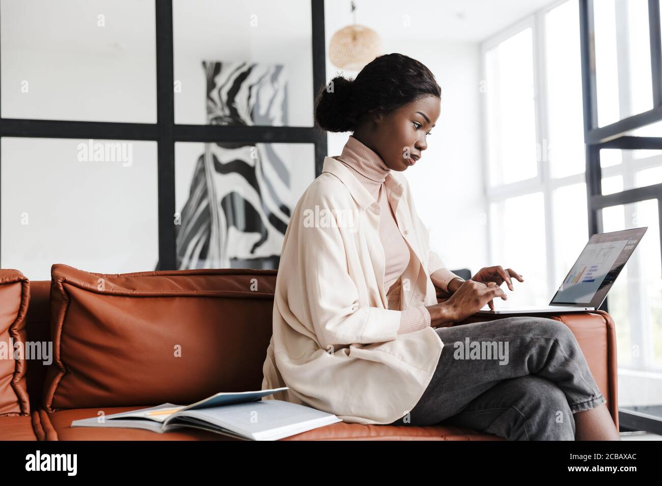 Attractive Young Pensive African Woman Sitting On A Couch At Home