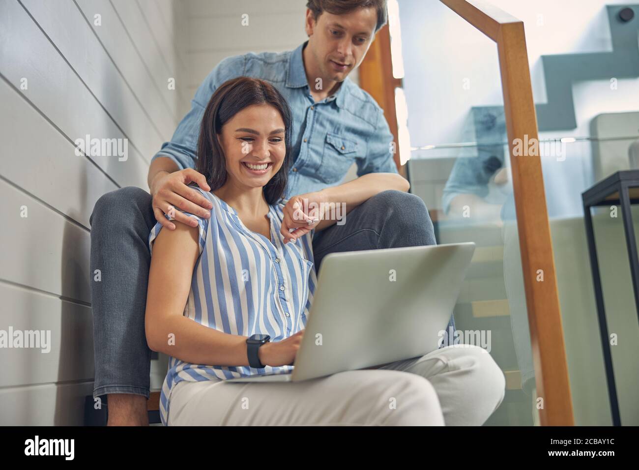 Pretty smiling lady with handsome man watching something on the laptop ...