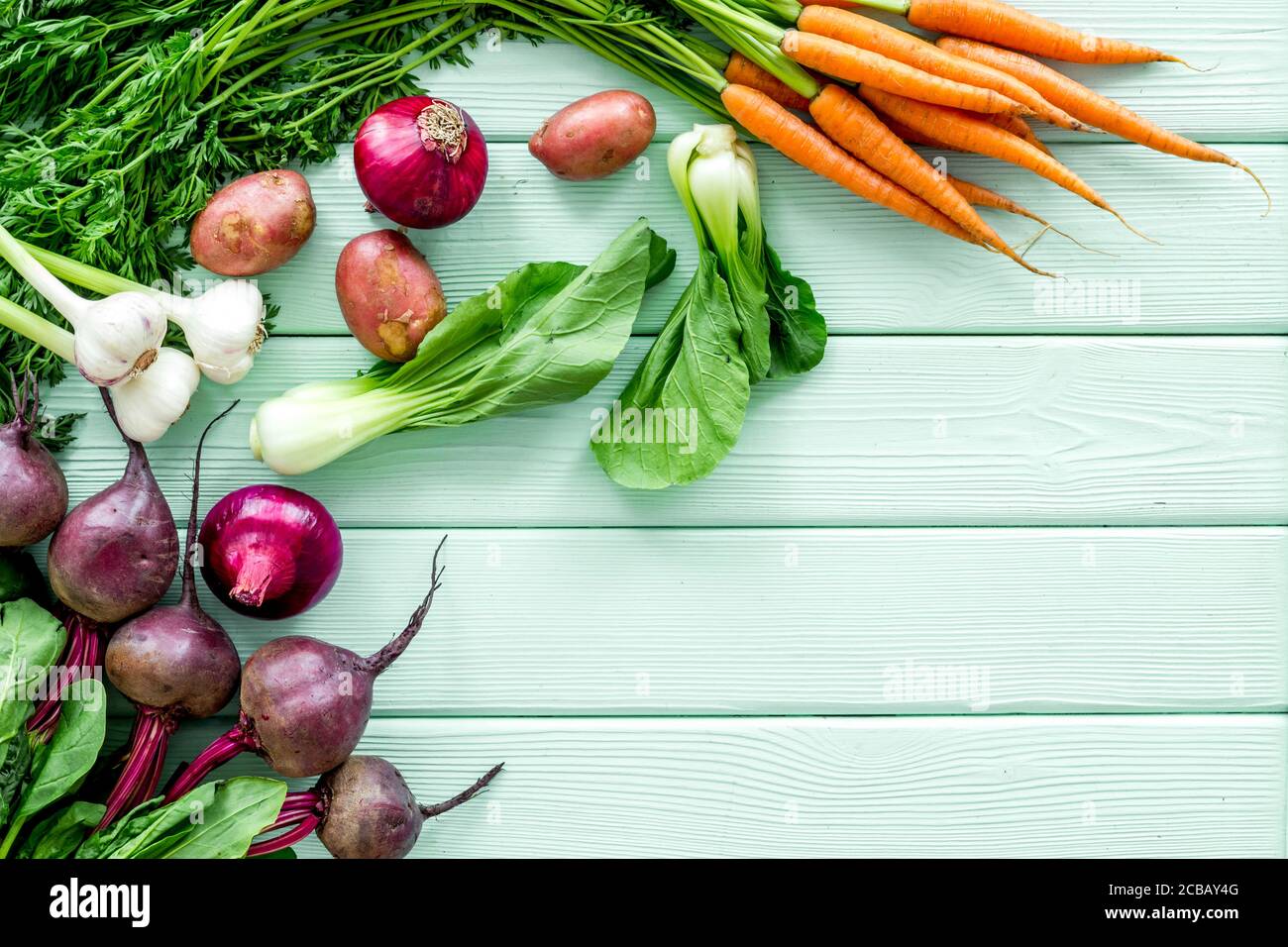 Flat lay of fresh vegetables and greenery on green table top-down copy ...
