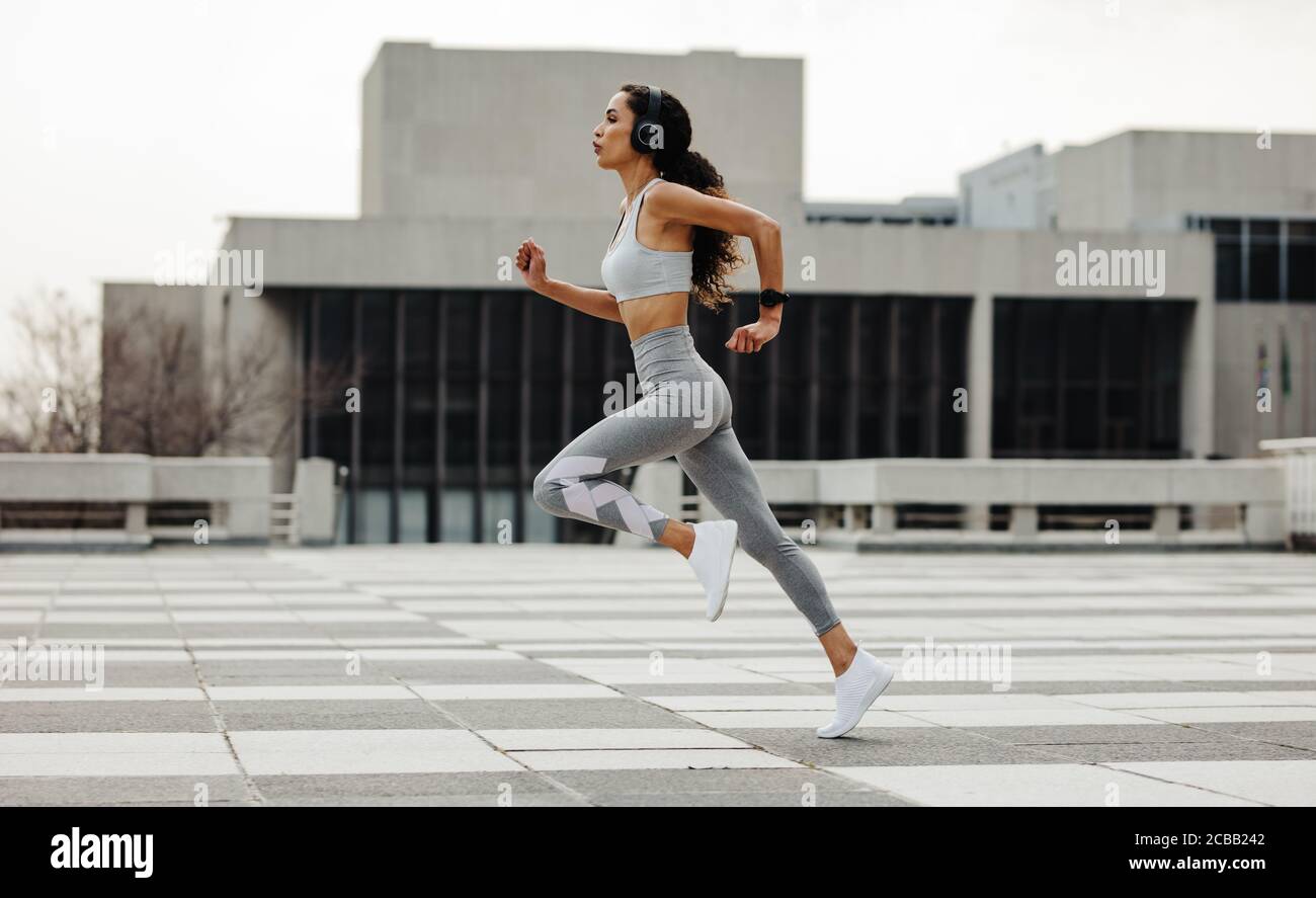 Full length shot of a sports woman sprinting in the city. Woman in ...