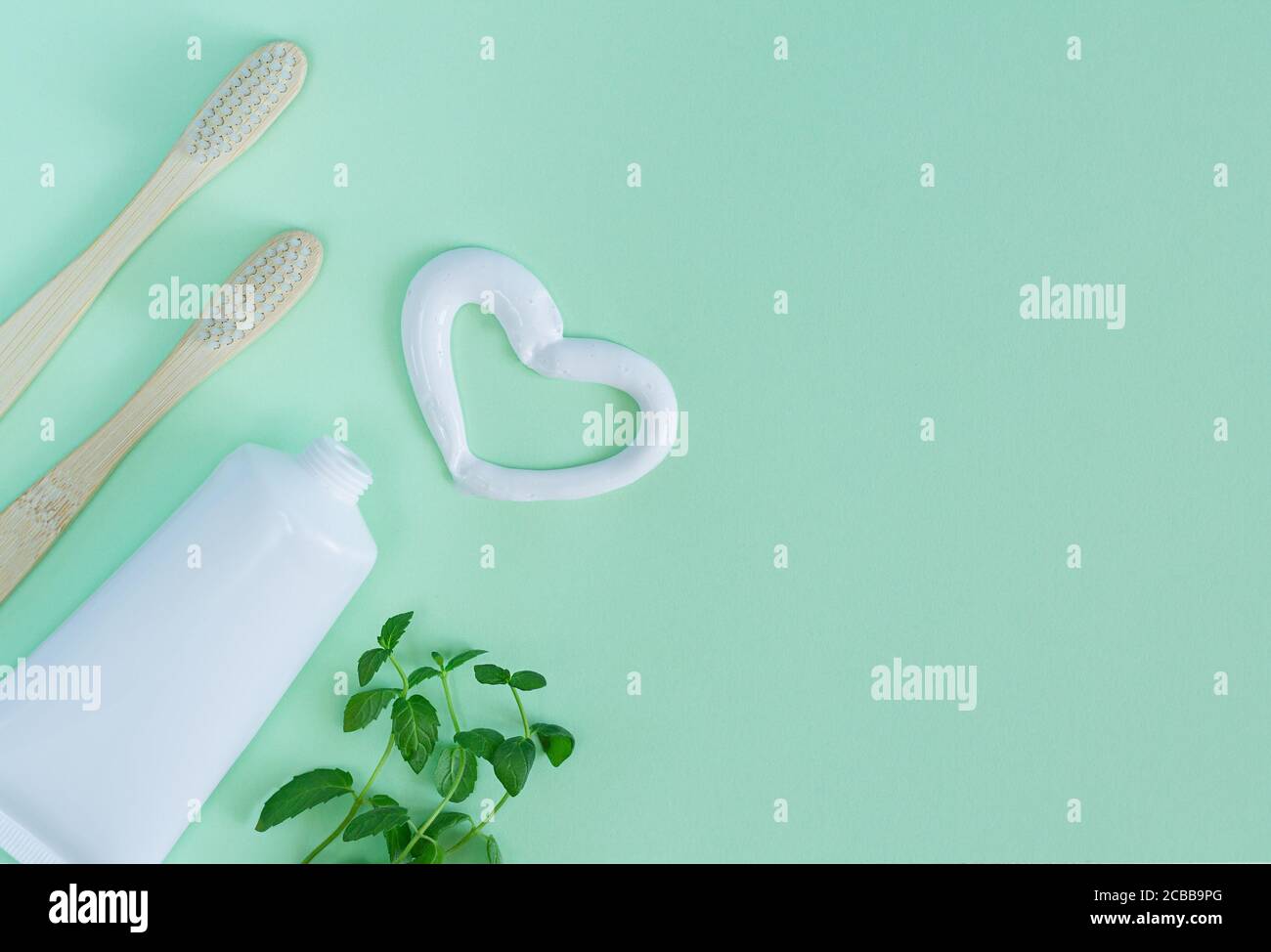 Bamboo toothbrushes, white tube of toothpaste, mint leaves on light ...