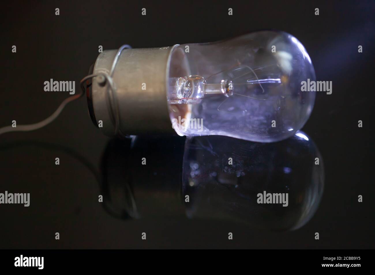 View of a lightbulb laying on its side against a black reflective ...