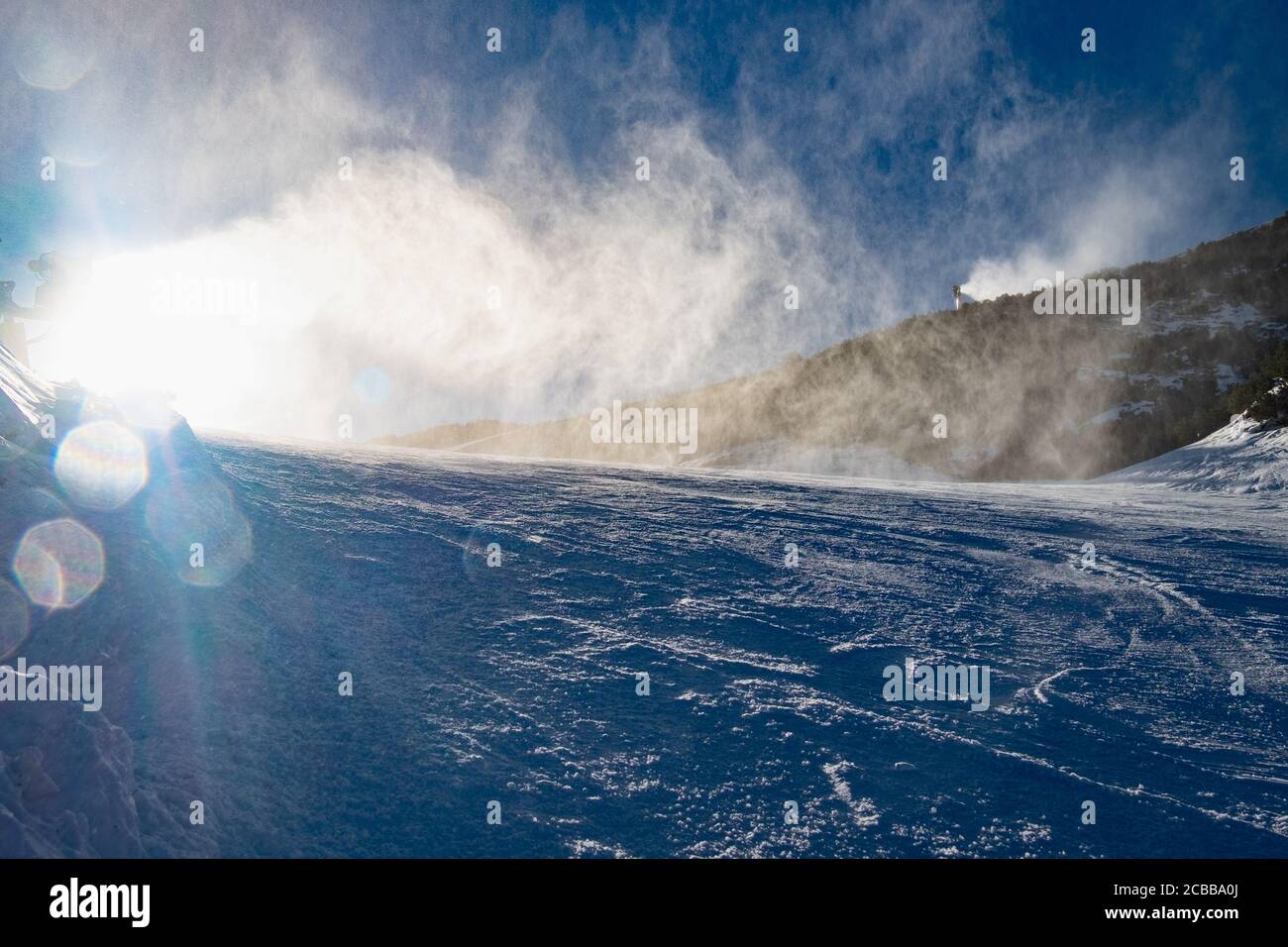 Heavy cloud of snow flakes bellow working snowcanon. The maintenance ...