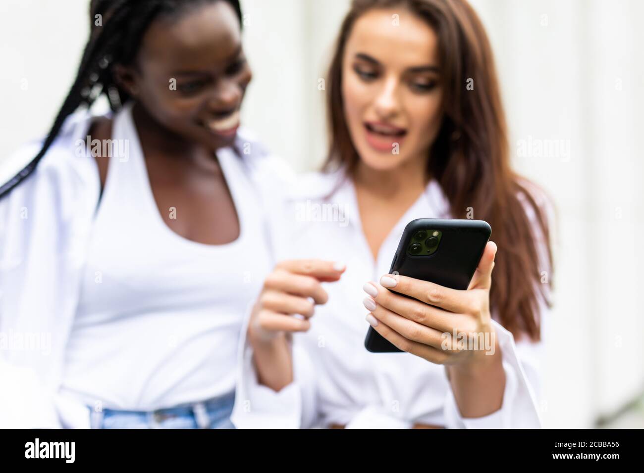 Two Beautiful Women Sending Messages with Mobile Stock Photo - Alamy