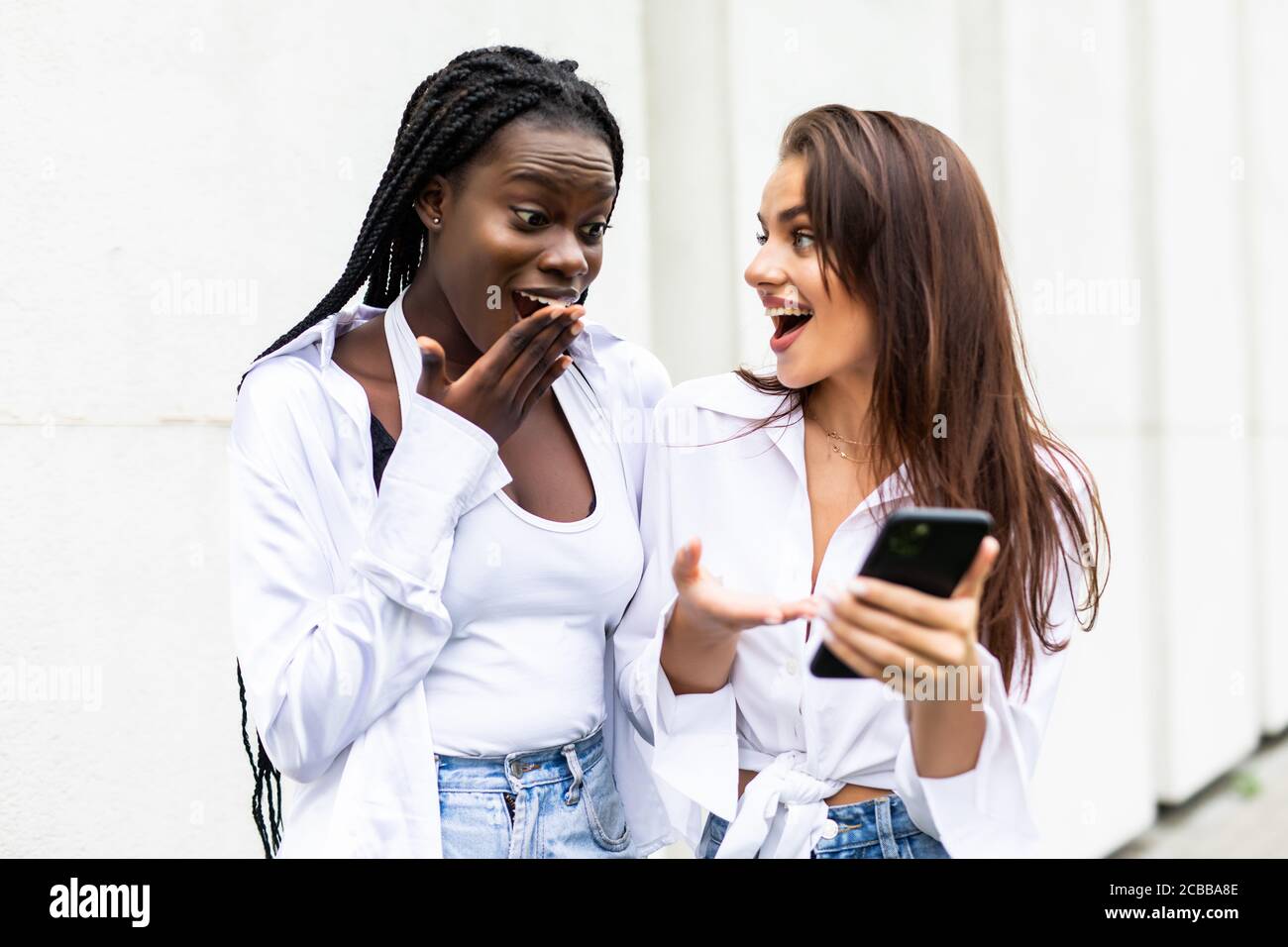 Two Beautiful Women Sending Messages with Mobile Stock Photo - Alamy