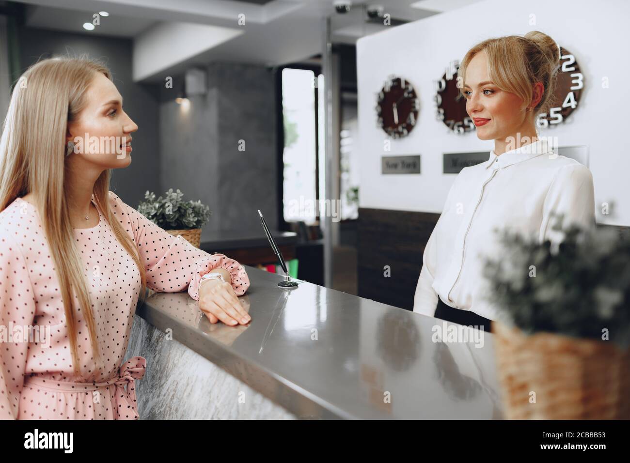 Blonde woman hotel guest checking-in at front desk in hotel Stock Photo ...
