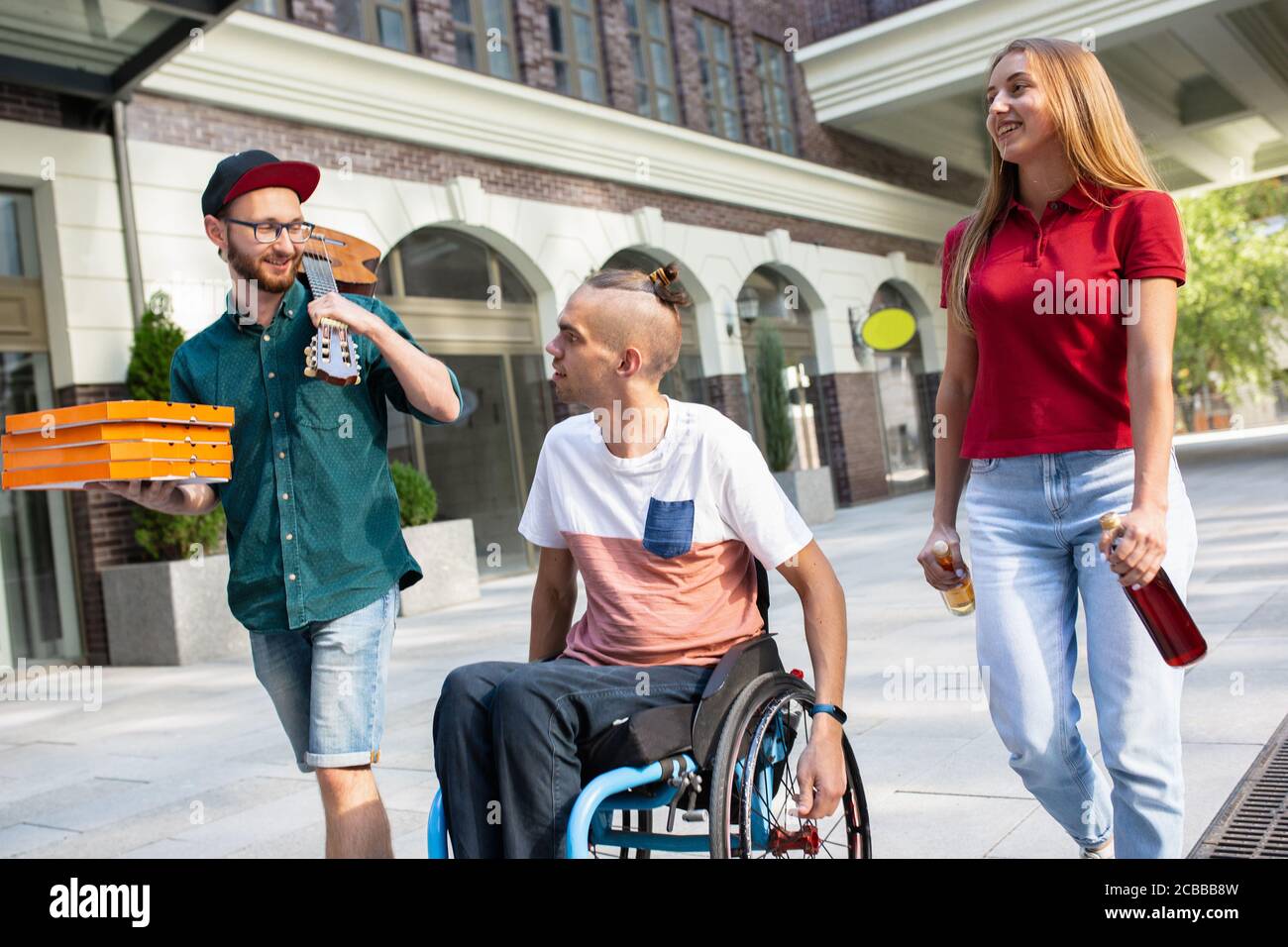Group of friends taking a stroll on city's street in summer day ...