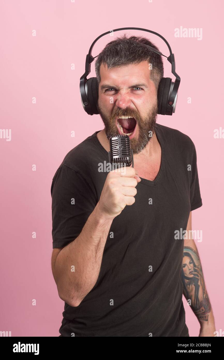 Man sings into microphone on pink background. Dj with beard wears ...