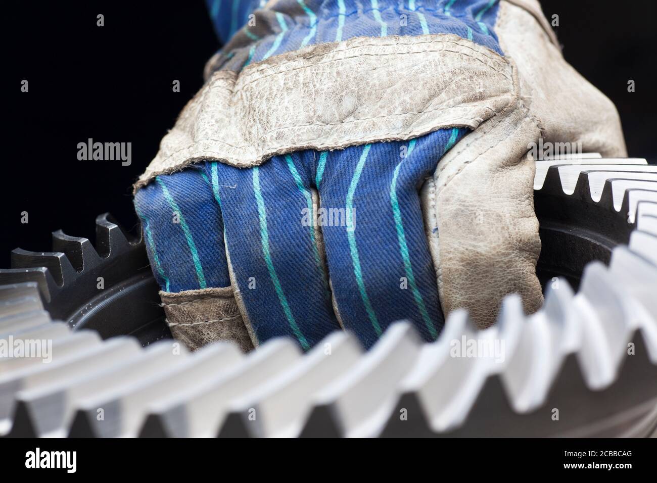 Hand of a mechanic carrying a big cog wheel - dark background Stock ...