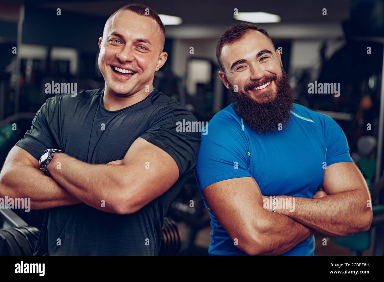 Two smiling fit men bodybuilders standing side to side in a gym Stock ...