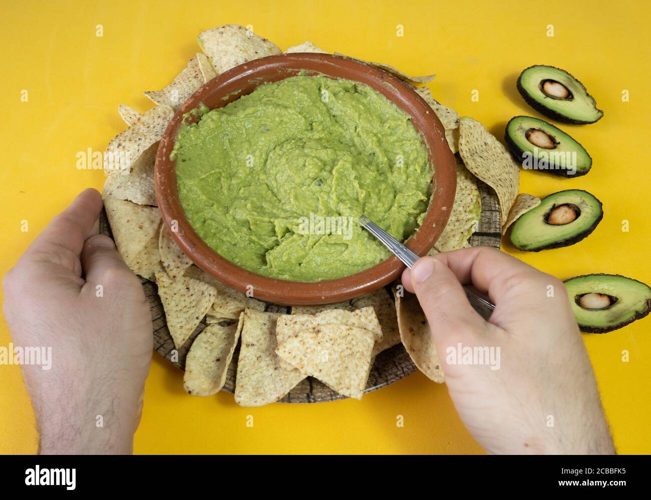 Man eating a Mexican delicious nachos with guacamole on a yellow ...