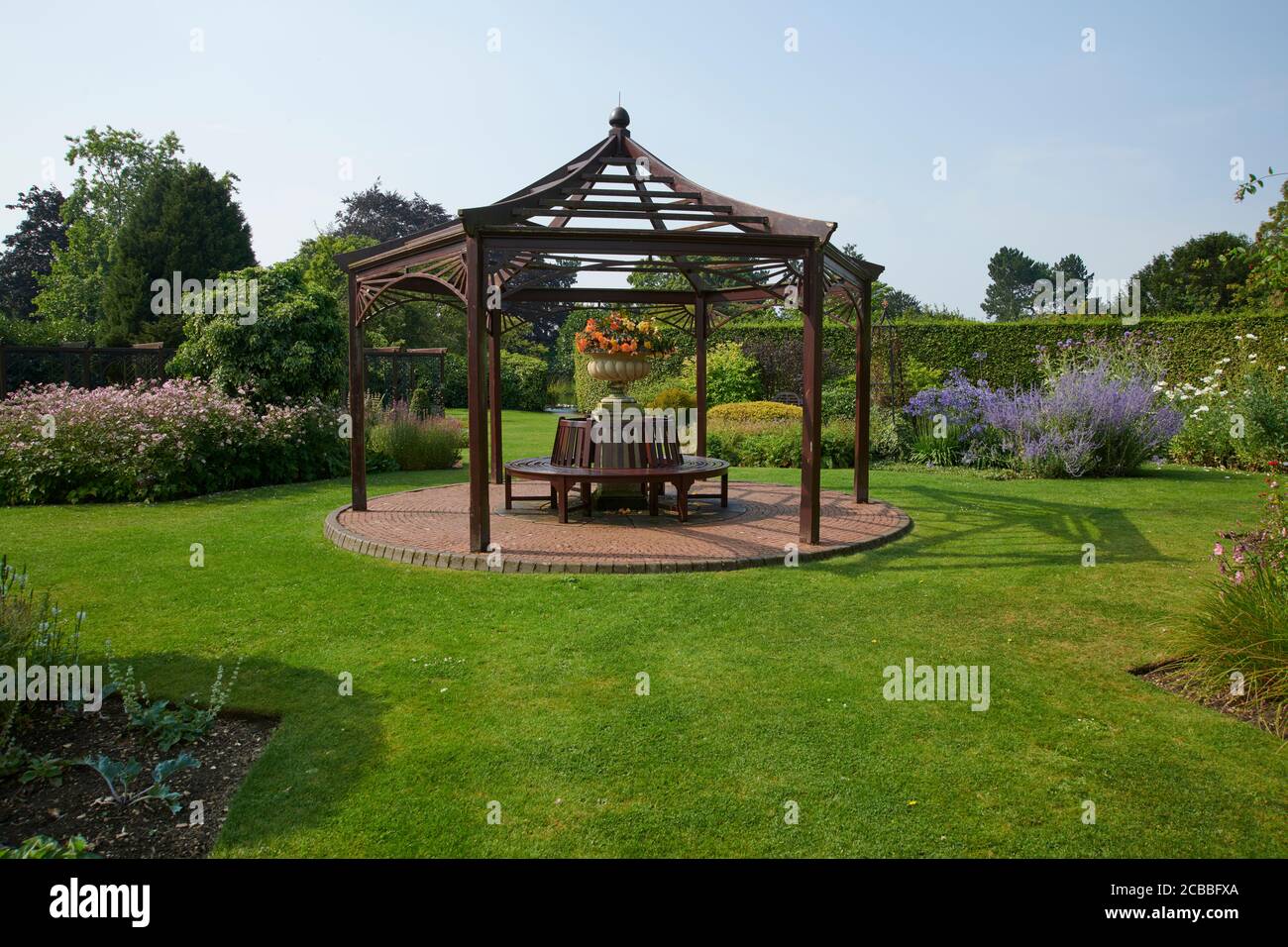 Wooden pergola and flower borders during the summer, in a walled garden ...