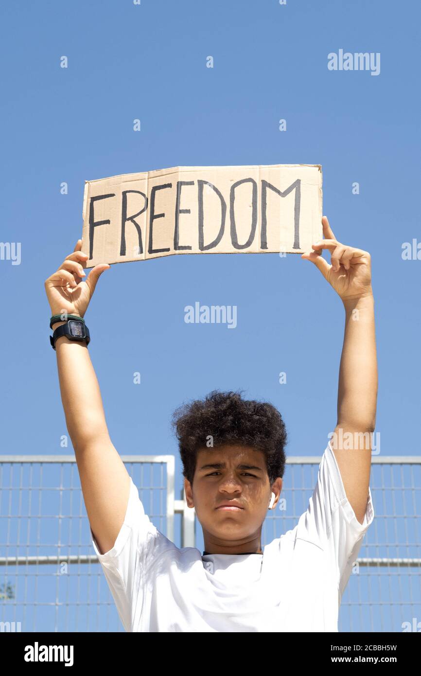 Afro teenage boy with a sign in his hands with the slogan: freedom ...