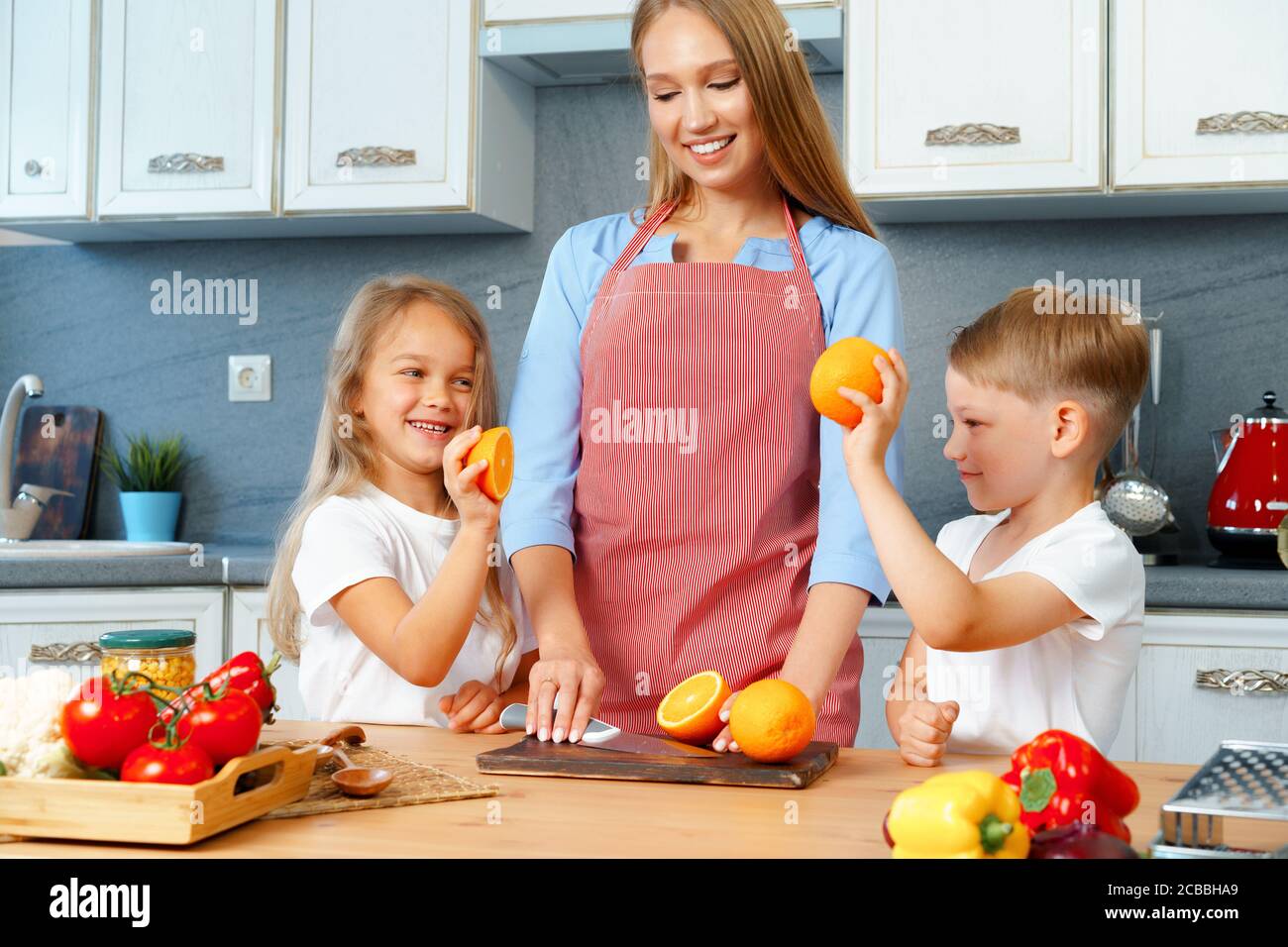 Mother cooking with her children in kitchen Stock Photo - Alamy