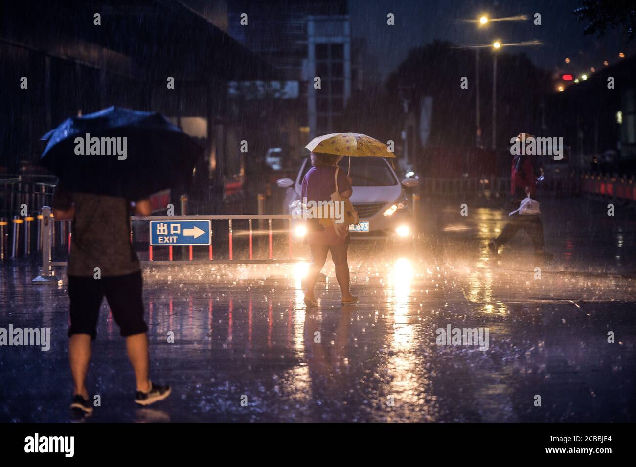 Beijing, China. 12th Aug, 2020. People walk in rain in Daxing District ...