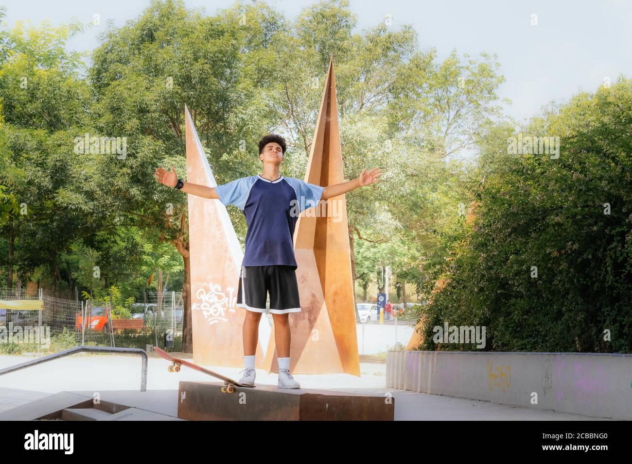 Skater young boy leaning on his skateboard and holding his hands in the ...