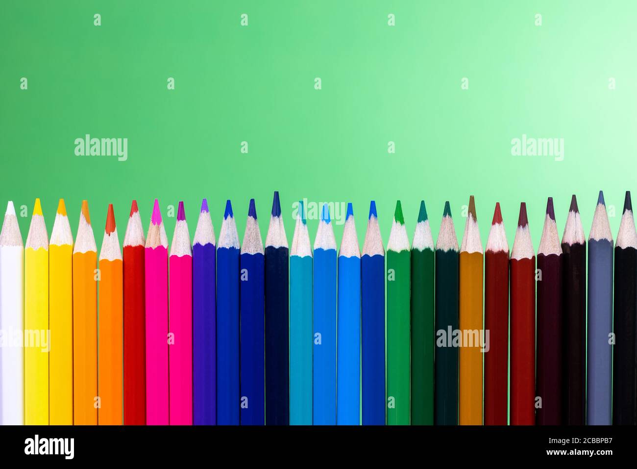 close up of colored pencils aligned vertically with green background ...