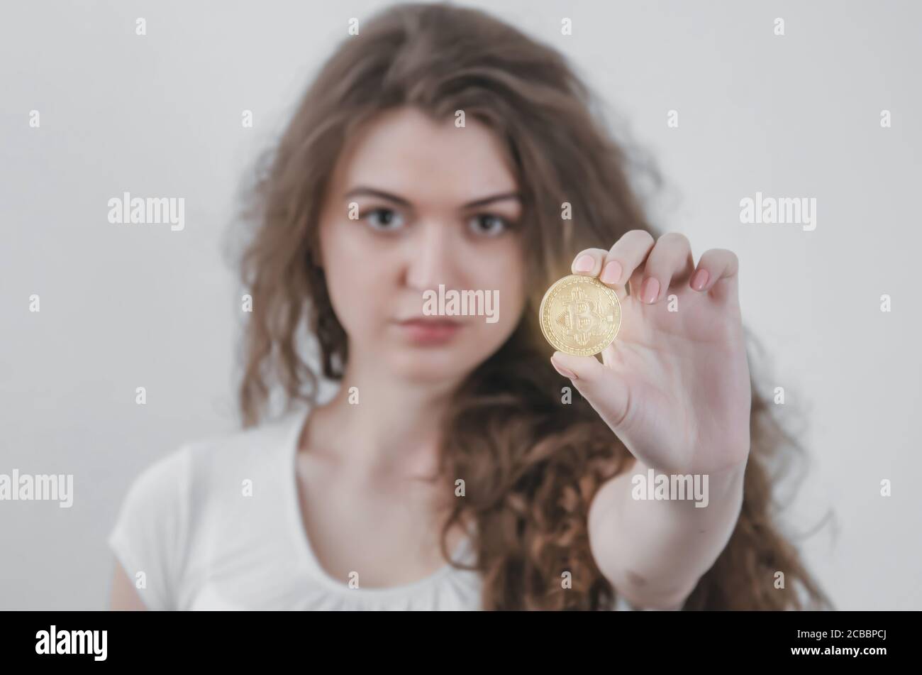 Young woman holds bitcoin coin in her hand, demonstrates financial ...