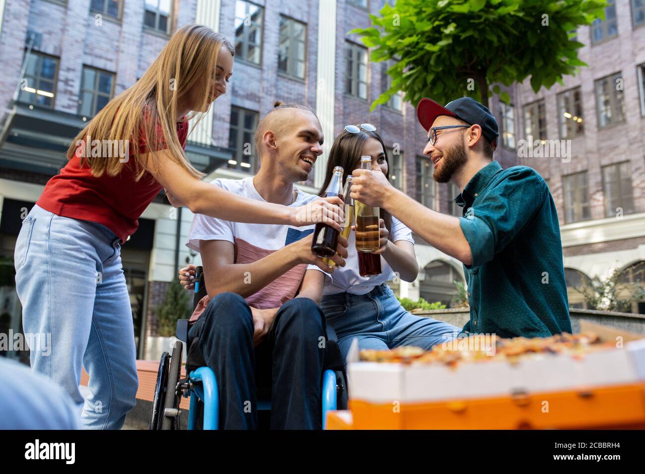 Bottles clinking. Group of friends taking a stroll on city's street in ...