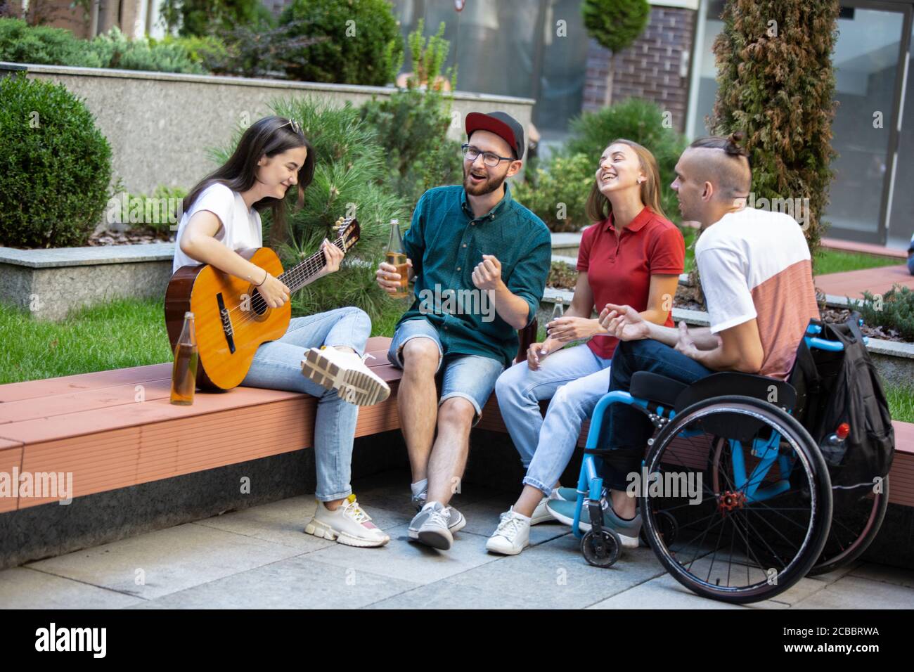 Drinks and songs. Group of friends taking a stroll on city's street in ...