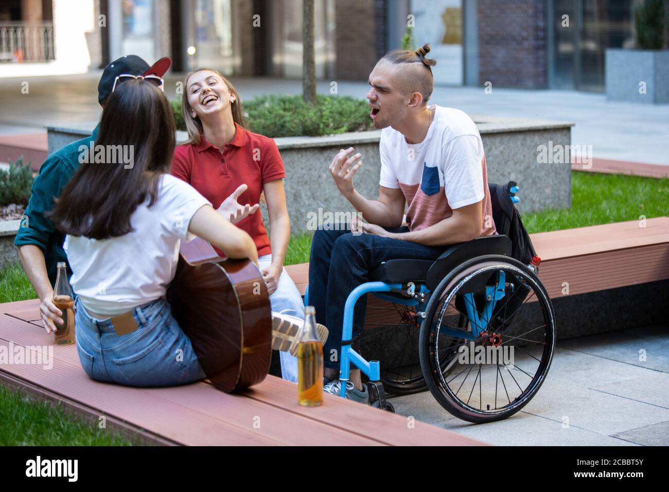 Drinks and songs. Group of friends taking a stroll on city's street in ...