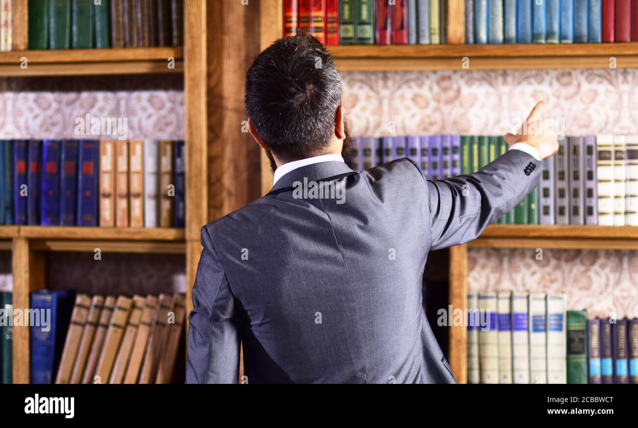 Back view of man standing and searching book in library Stock Photo - Alamy