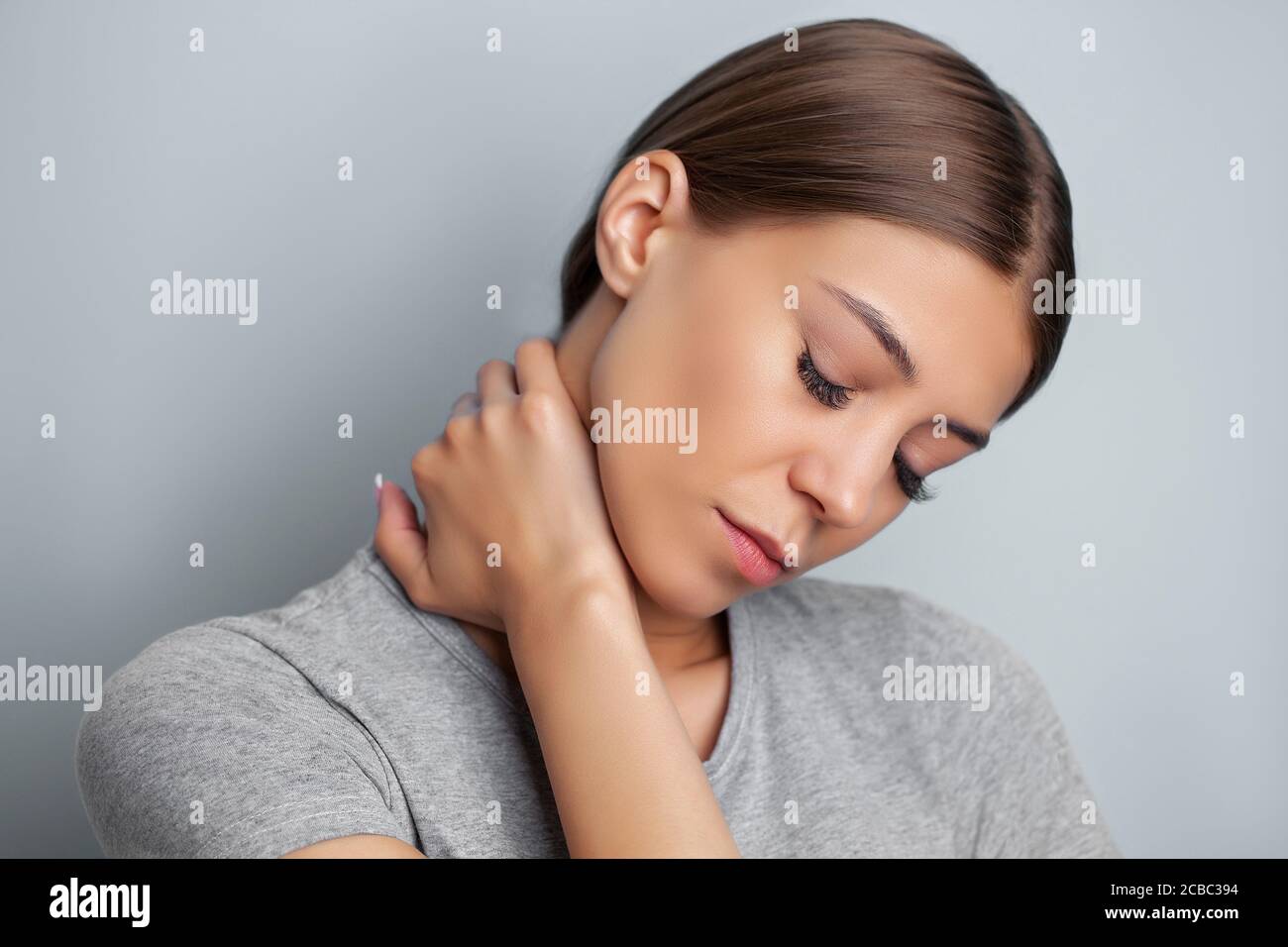 Young woman experiencing severe neck pain while holding her hands Stock ...