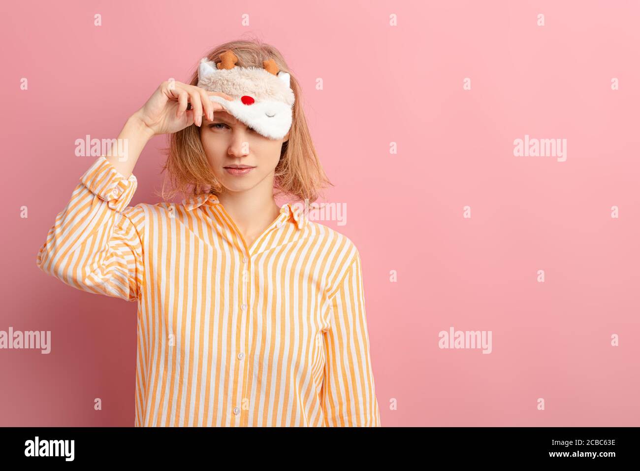 portrait of sleepy young woman with short hair, wearing pajamas and ...