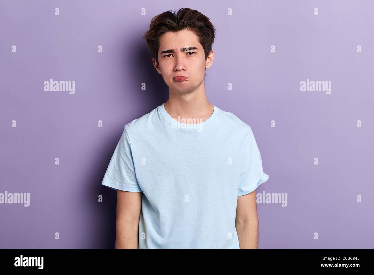 funny young man blowing cheeks, close up portrait, isolated blue ...