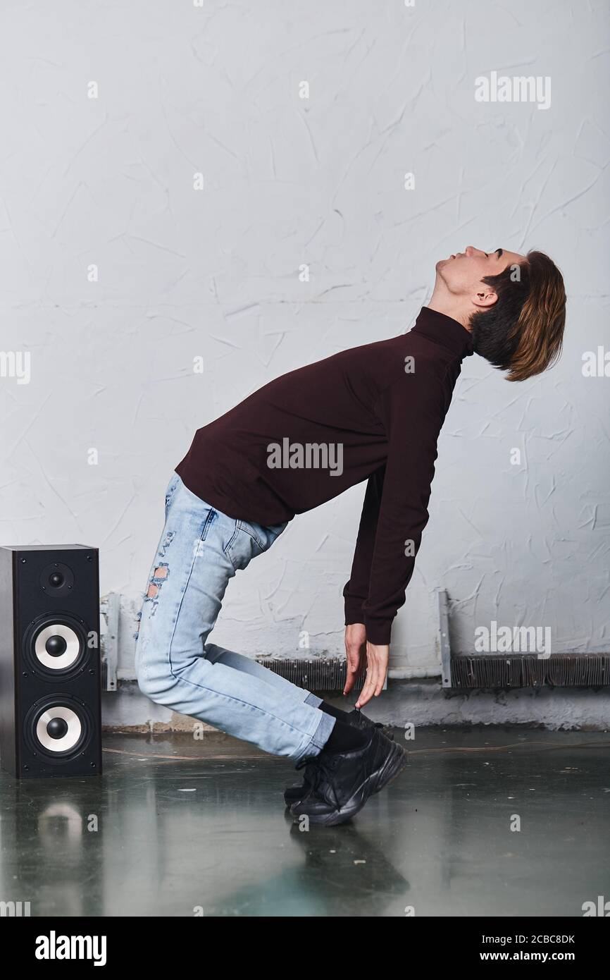 young flexible man performing a stunt in the dance studio. performance ...