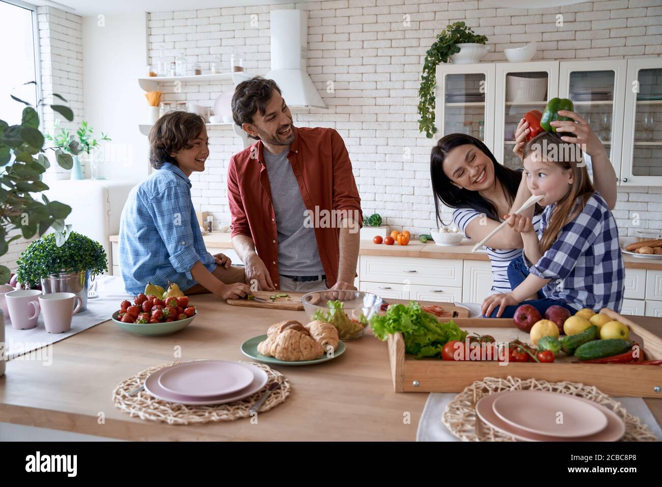 Lovely family with happy kids having fun while cooking together in the ...