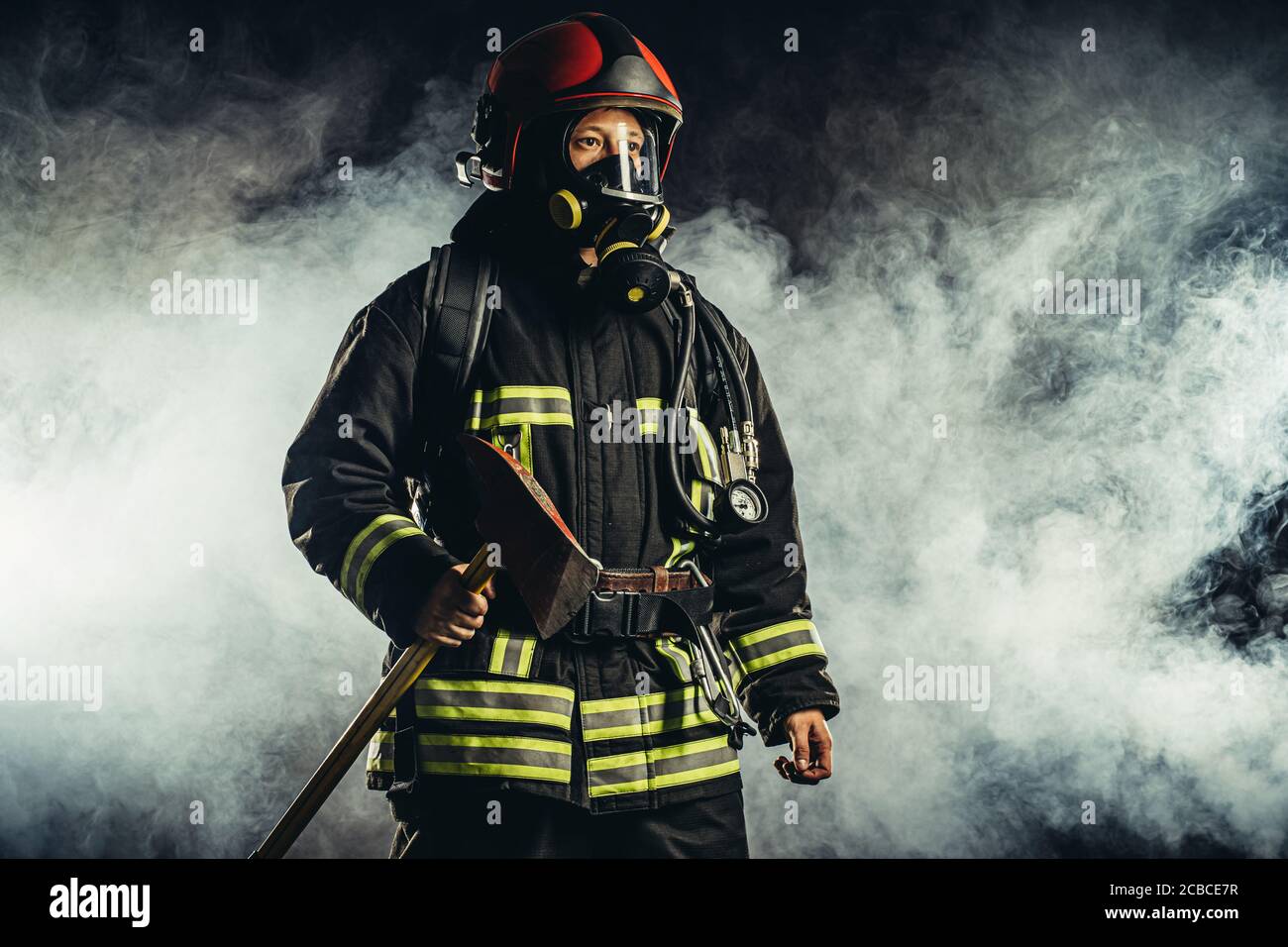 young caucasian fireman holding hammer, risking his life to save people ...