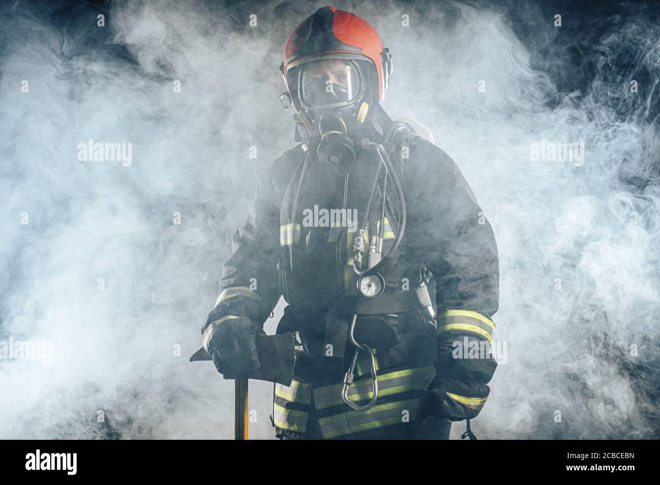 young fireman in protective coat using special equipment for fire ...